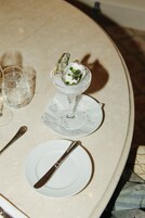 Uma mesa com uma sobremesa em um copo, um prato e um copo de água.