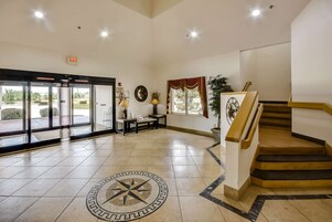 Um hall amplo com piso de azulejos, escada e uma grande porta de vidro.