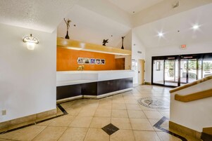 Uma área de recepção com balcão, luminária fixada na parede e porta que dá para o exterior.