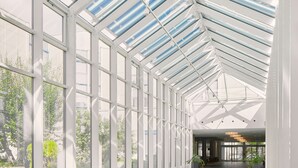 Um interior moderno e espaçoso, com teto de vidro, grandes janelas e decoração em branco, clean.