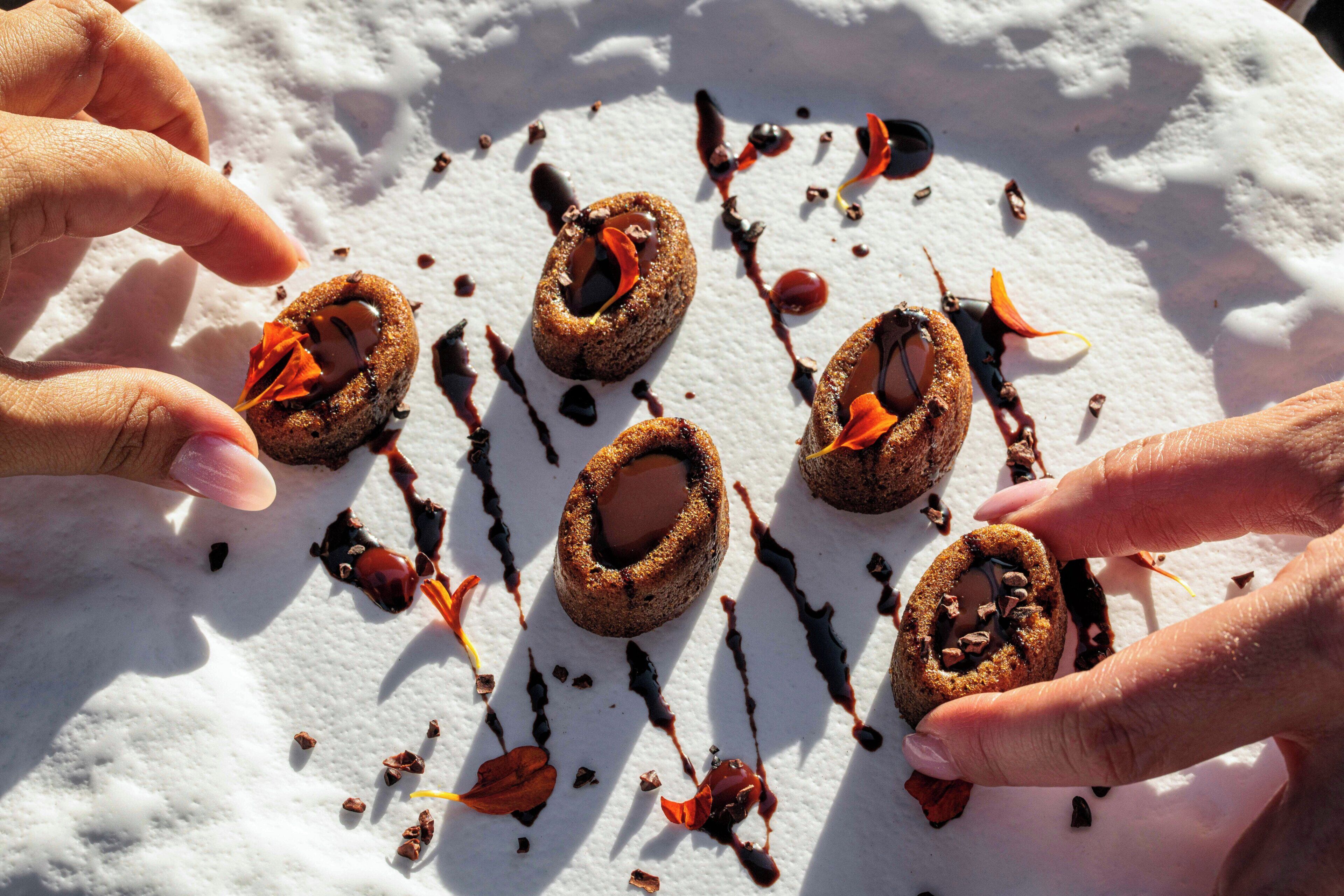 Uma sobremesa apresentada sobre uma superfície branca, decorada com chocolate e caramelo.