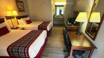 Quarto de hotel com duas camas, uma escrivaninha e um espelho.