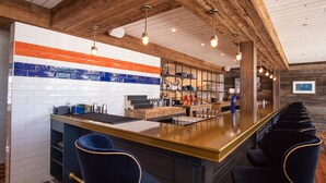 Uma área de bar com teto de madeira, revestimento de azulejos e banquetas.