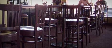 Um restaurante com várias cadeiras e mesas de madeira.