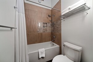 Uma casa de banho com banheira, chuveiro e sanita.