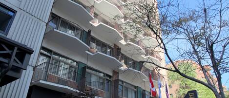 Um hotel com fachada moderna, várias varandas e uma placa indicando ser hotel.