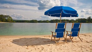 Uma praia com duas cadeiras de praia azuis e um guarda-sol azul.