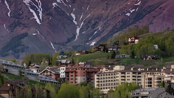Paisagem montanhosa com mistura de edifícios residenciais e comerciais, incluindo hotéis e casas, com uma estrada serpenteando pela região.
