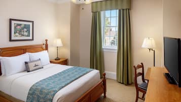 Quarto de hotel com cama, duas luminárias laterais, televisão, janela com cortinas e um quadro na parede.