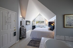 Quarto com cama grande, lareira, janela com persianas e banheiro com banheira.