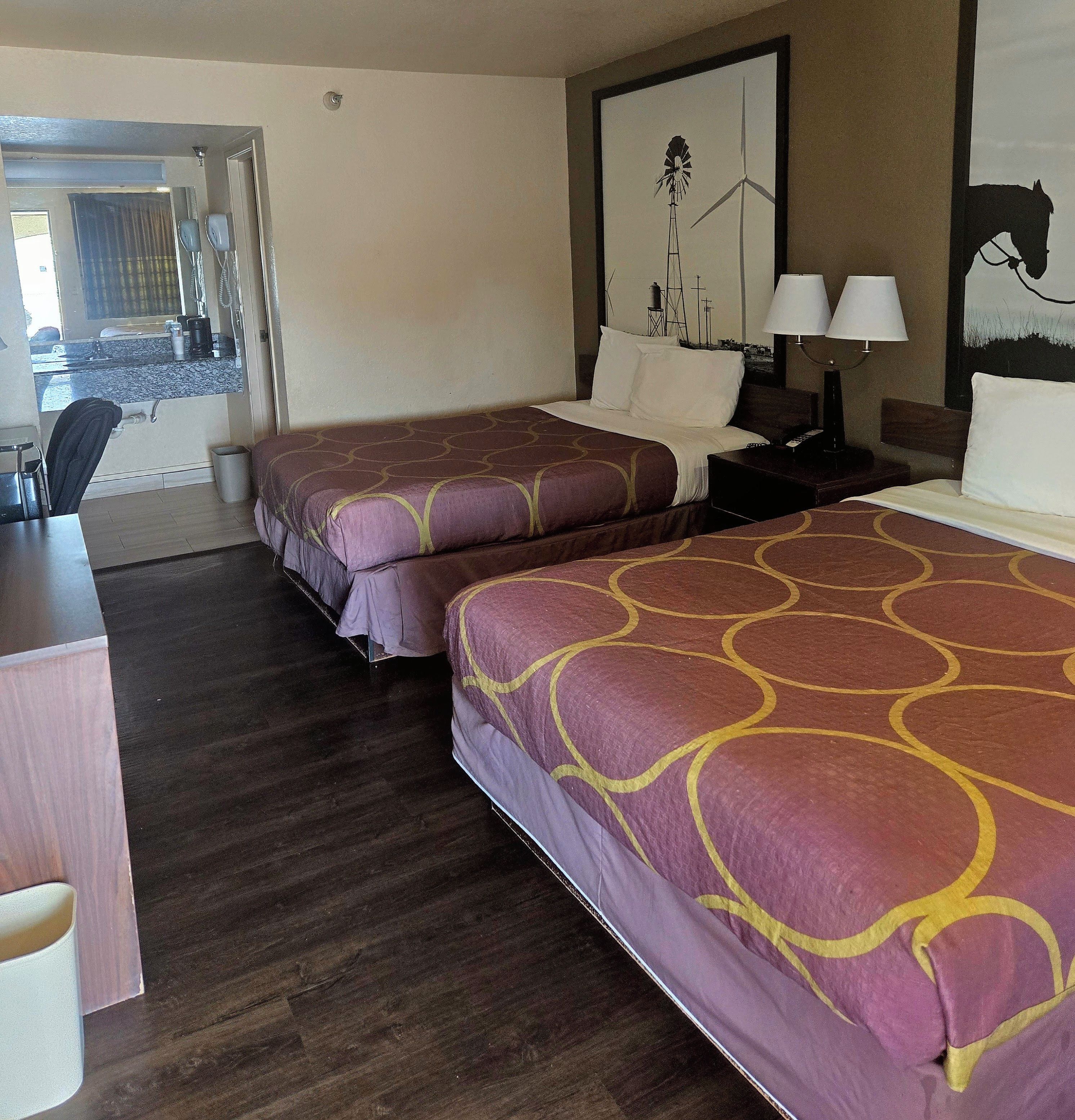 Quarto de hotel com duas camas, uma escrivaninha e vista para o exterior.