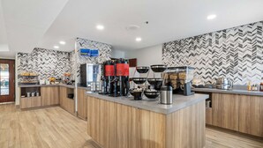 Uma cozinha moderna com ilha central, equipada com máquinas de café, chaleira e diversos utensílios de cozinha.