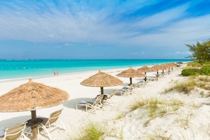 Na praia, areia branca, barracas de praia de cortesia, espreguiçadeiras