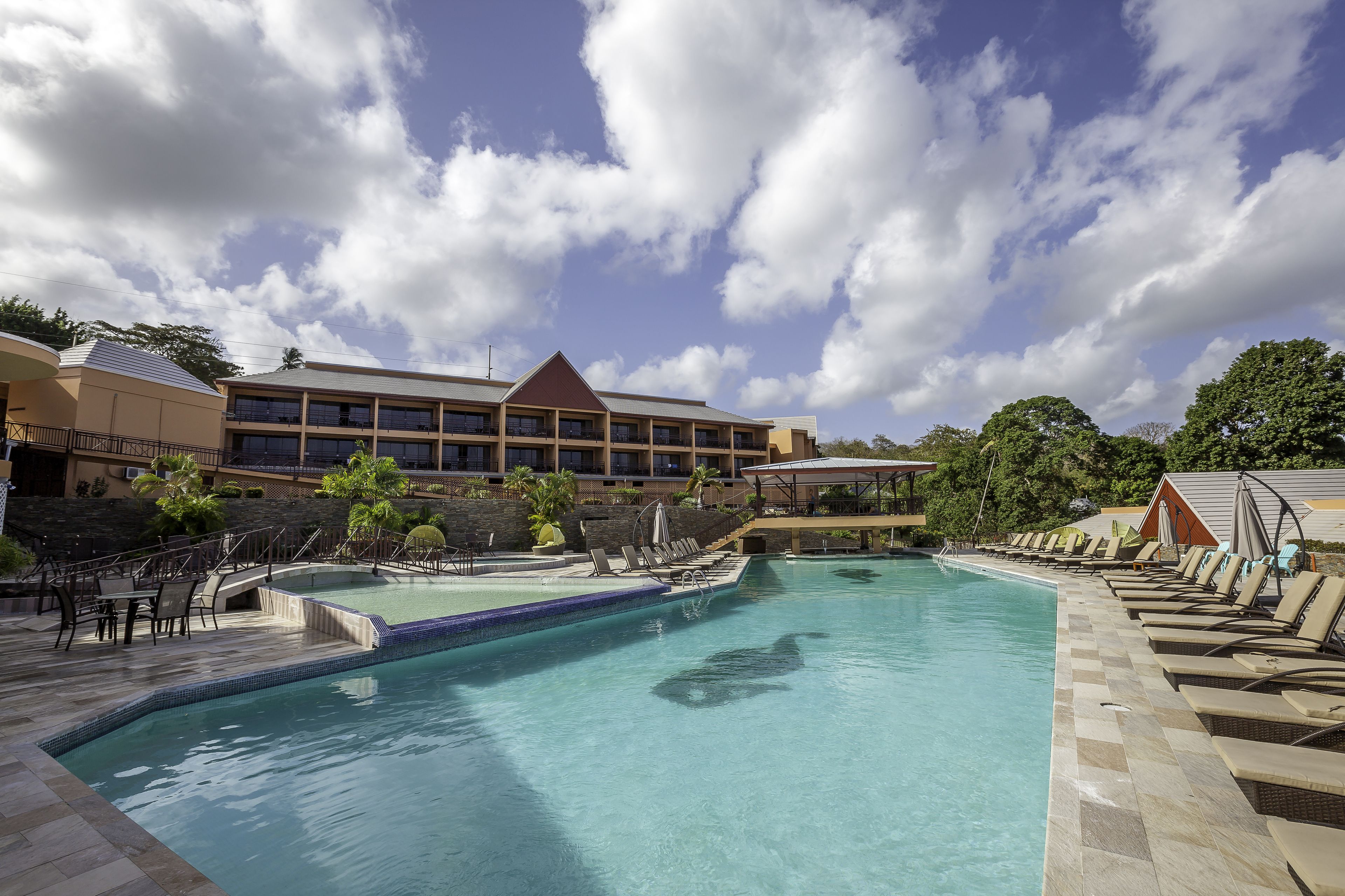 Um hotel com piscina, espreguiçadeiras e vista para a paisagem ao redor.