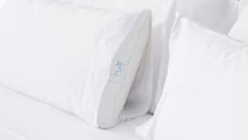 Uma cama branca com almofadas, uma das quais tem a etiqueta com a inscrição 'Pure'.