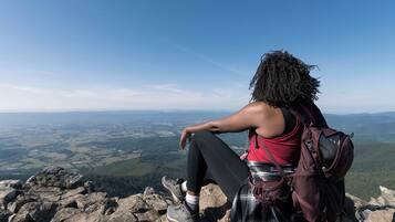 Uma pessoa sentada numa rocha com vista para um vale.