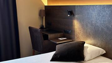 Quarto de hotel com cama, escrivaninha e abajur.