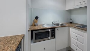 Uma cozinha compacta com micro-ondas integrado, uma pia e suporte para facas.