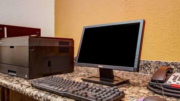 Um computador com teclado e rato, um telefone e um aparelho de fax sobre uma bancada de granito.