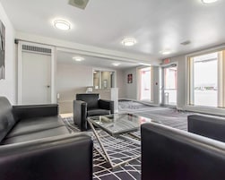 Um saguão de hotel com assentos, uma mesa de recepção e vista para o exterior.