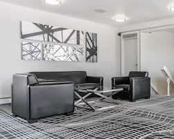 Quarto moderno com sofá de couro preto, mesa de centro de vidro e arte abstrata nas paredes.