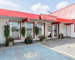 Um edifício com telhado vermelho e uma placa com a inscrição 'EconoLodge'. Há plantas em vasos na frente da entrada.