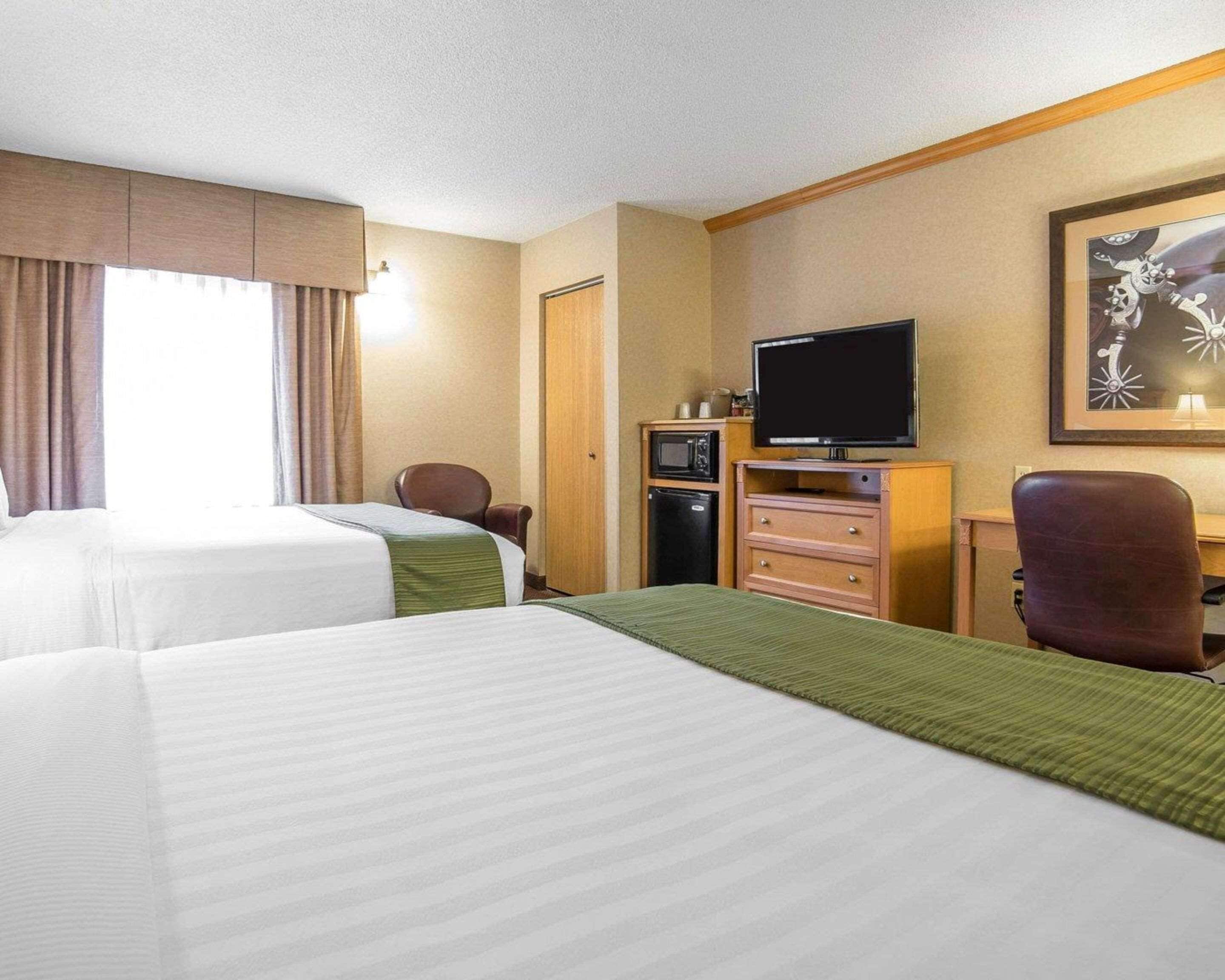 Quarto de hotel com duas camas, televisão, escrivaninha e uma cadeira.