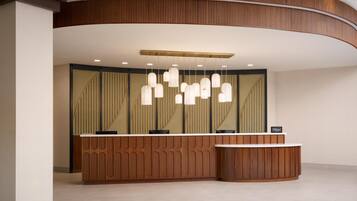 Uma receção de hotel moderna, com acabamento em madeira e design curvo.