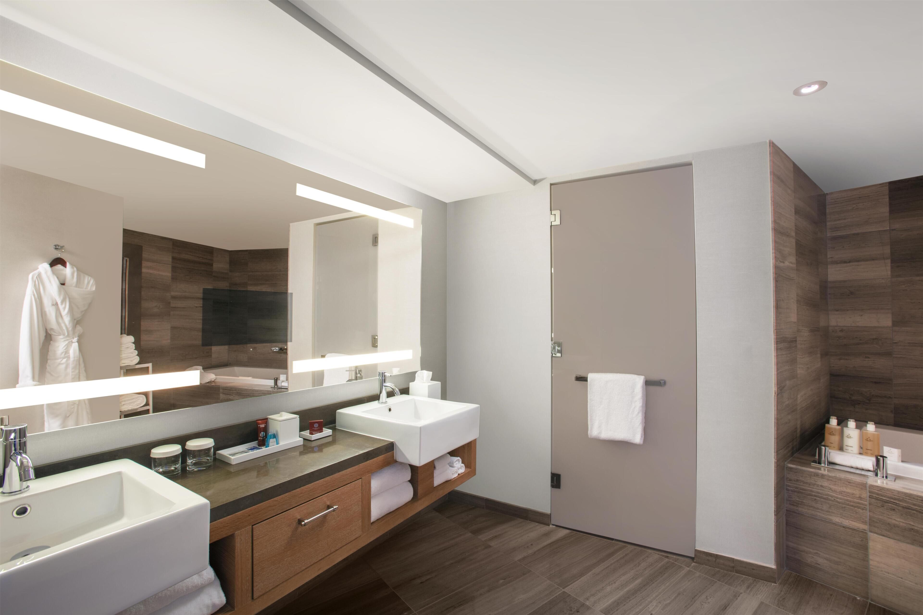 Uma casa de banho moderna com duas pias, um espelho grande e um chuveiro de entrada direta.