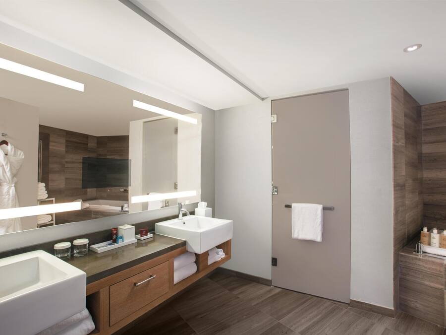 Uma casa de banho moderna com duas pias, um espelho grande e um chuveiro de entrada direta.