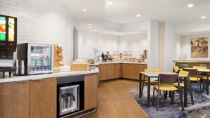 Uma área de pequeno-almoço moderna com serviço de buffet, lugares sentados e um quadro grande na parede.