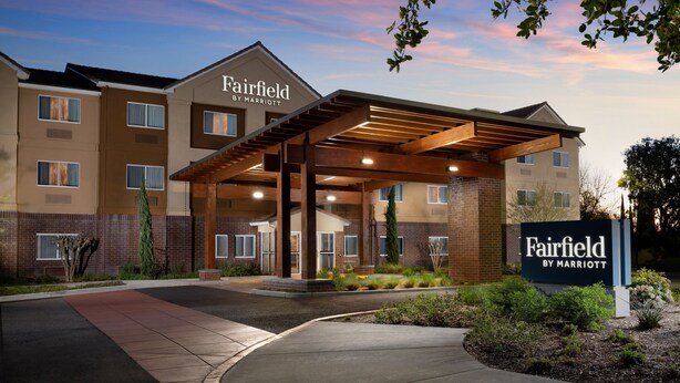 Entrada de um hotel Marriott Fairfield com galeria coberta, fachada de tijolos e área ajardinada.