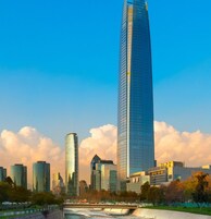Paisagem urbana com edifícios modernos altos, incluindo um arranha-céu imponente com design curvo característico.