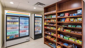 Espaço de máquinas de venda automática com várias prateleiras repletas de petiscos e bebidas.