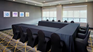 Uma sala de conferências com uma mesa comprida e cadeiras, janelas amplas e obras de arte na parede.
