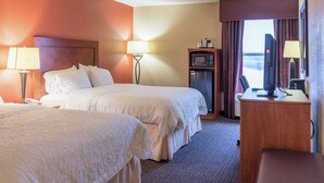 Quarto de hotel com duas camas, uma escrivaninha com computador, micro-ondas e televisão.