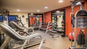 Academia com esteiras, aparelhos de musculação e diversos pesos livres.
