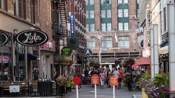 Rua repleta de lojas e restaurantes variados, incluindo um bar e uma loja de roupas.