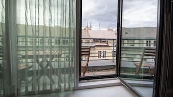 Janela com vista para edifícios e um banco de madeira do lado de fora.