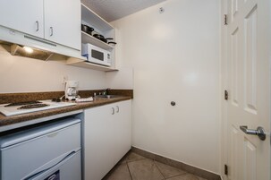 Uma cozinha compacta com armários brancos, micro-ondas, máquina de café e pia.
