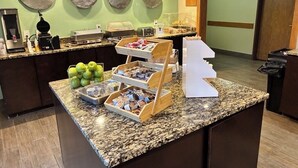 Um balcão de pequeno-almoço com diversas opções de comida e uma máquina de café.