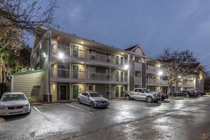 Edifício de vários andares com estacionamento, apresentando uma construção de dois andares com varandas e entrada no nível da rua.