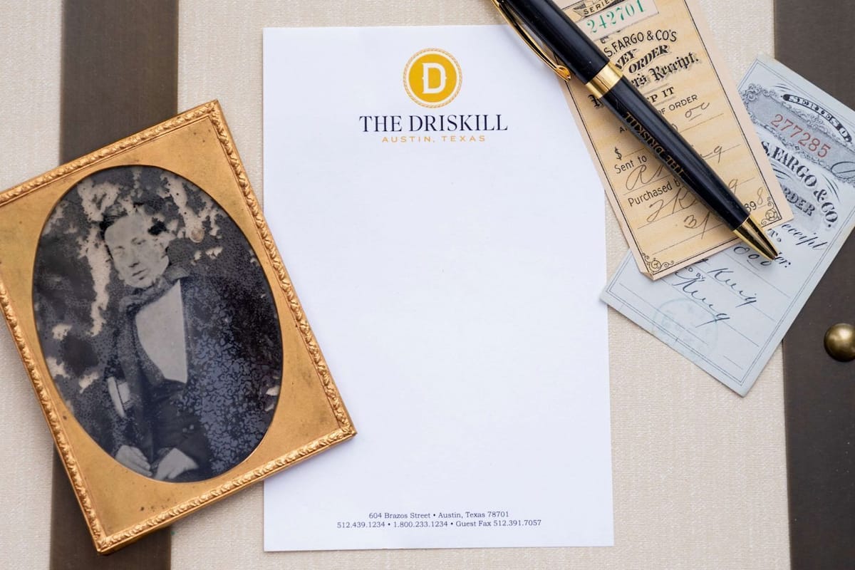 Cartão de visita do 'The Driskill' em Austin, Texas, uma caneta e algumas notas bancárias antigas.