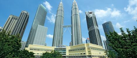 As Torres Petronas com edifícios modernos ao redor e uma área de parque.
