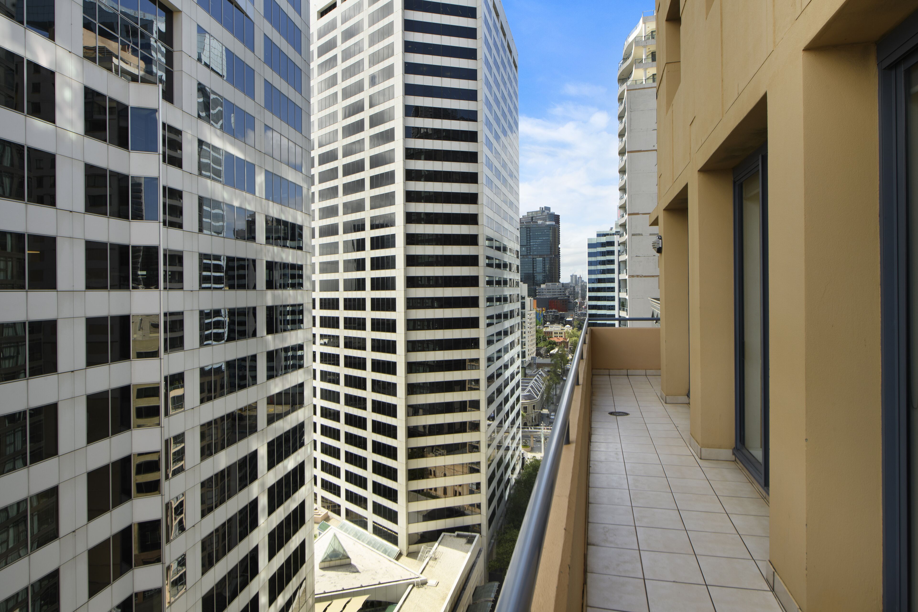 Um edifício alto com fachada de vidro moderna e varanda com piso de azulejos.