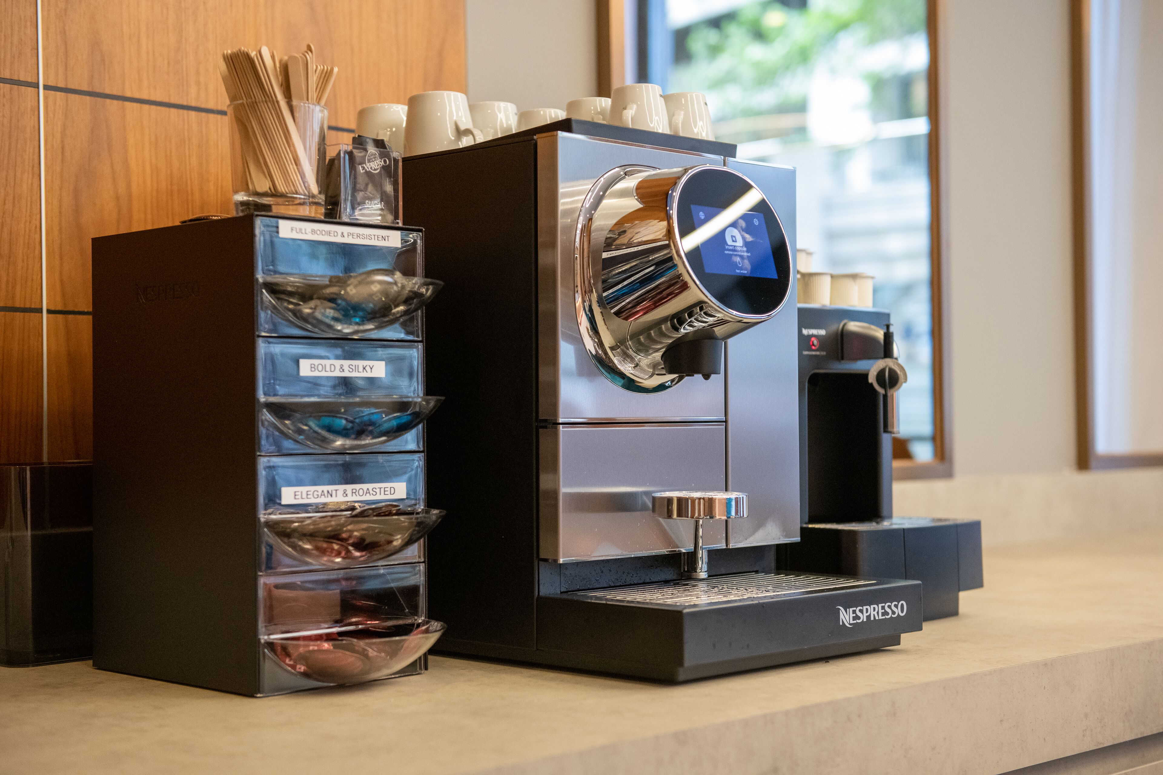 Máquina de café Nespresso com vários dispensadores de cápsulas, cada um identificado com diferentes tipos de café.