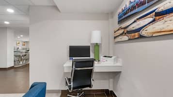 Um espaço de escritório moderno com uma mesa, cadeira e uma grande pintura de barcos na parede.