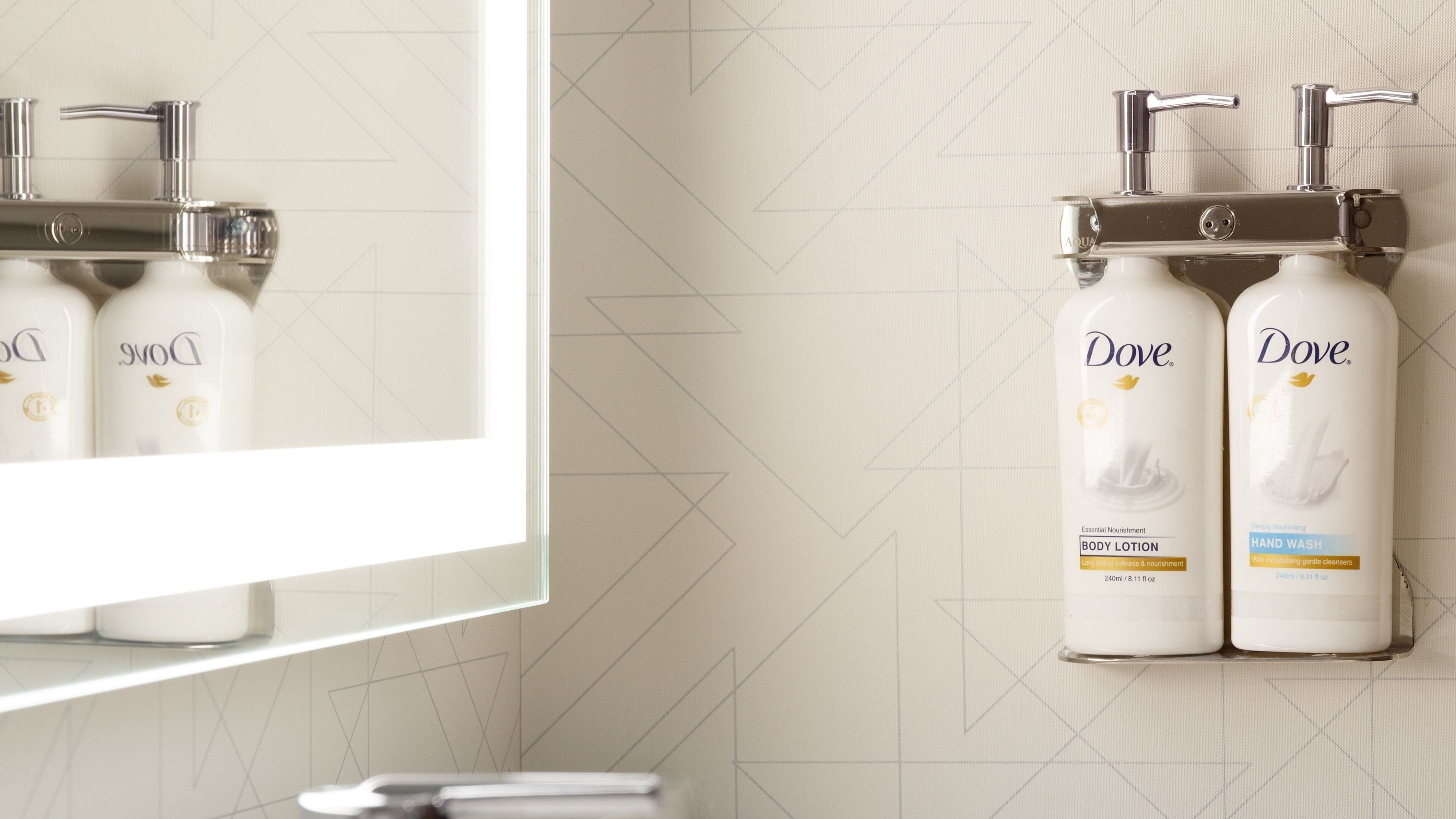 Casa de banho com loção corporal e gel de mãos Dove numa prateleira.