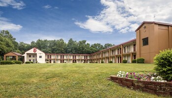 Um motel com pátio central, várias varandas e telhado vermelho.