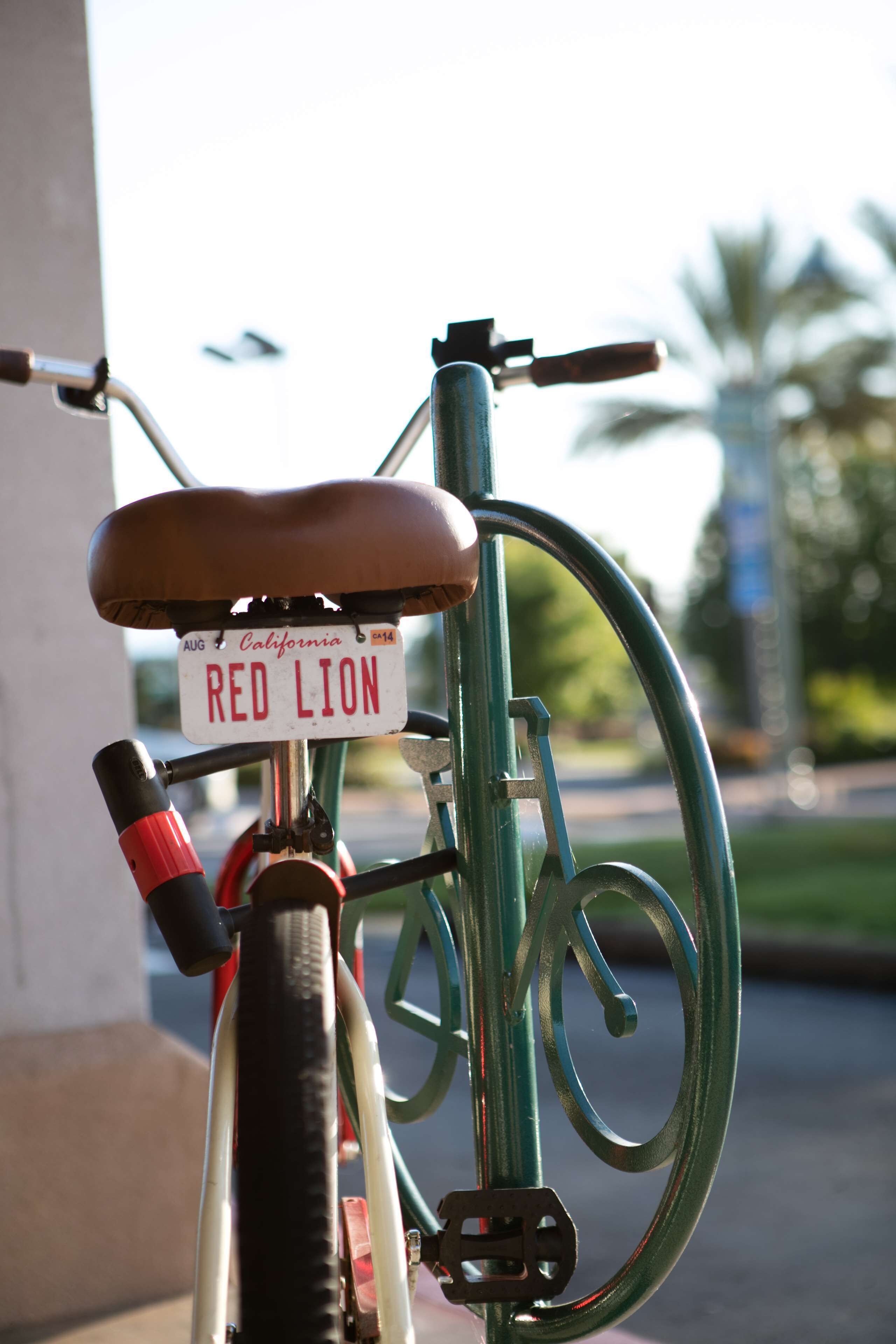 Bicicleta com placa de licença da Califórnia que diz 'RED LION' estacionada perto de um edifício.